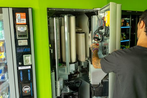 Male filling a coffee vending machine in a self-service grab shop in ...